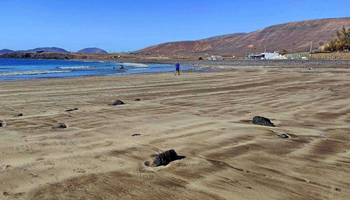 Two bathers fall into the water near the rocks on La Garita beach